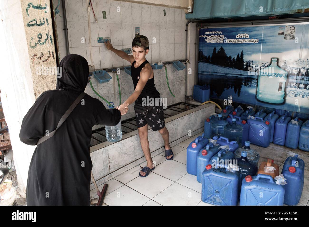 A Palestinian woman buying drinking water in the Sabra-Shatila refugee ...