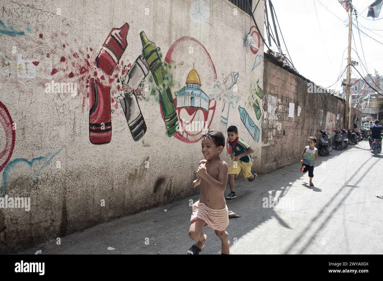 Palestinian Kids running the street in from of wall painting of the ...