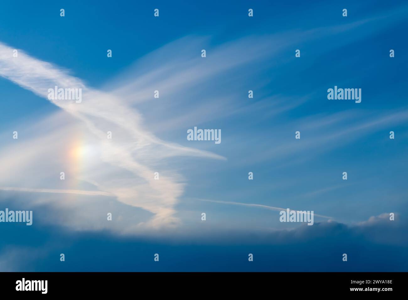 Sky with cirrus, stratus clouds, airplane trail and halo from the sun ...