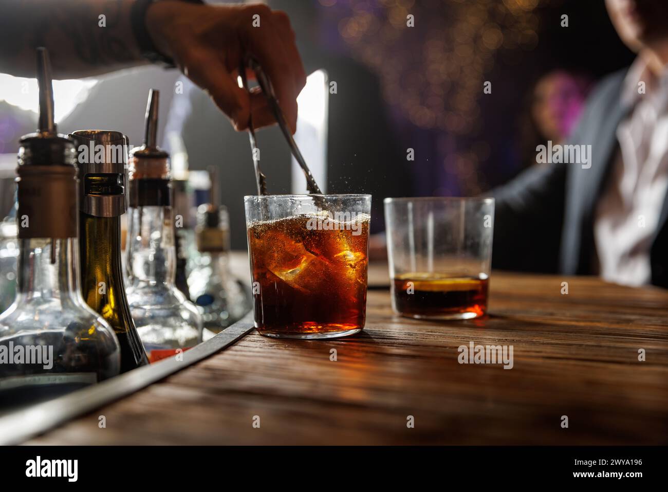 Gas bubbles of carbonated cola drink in a glass on a wooden bar counter ...