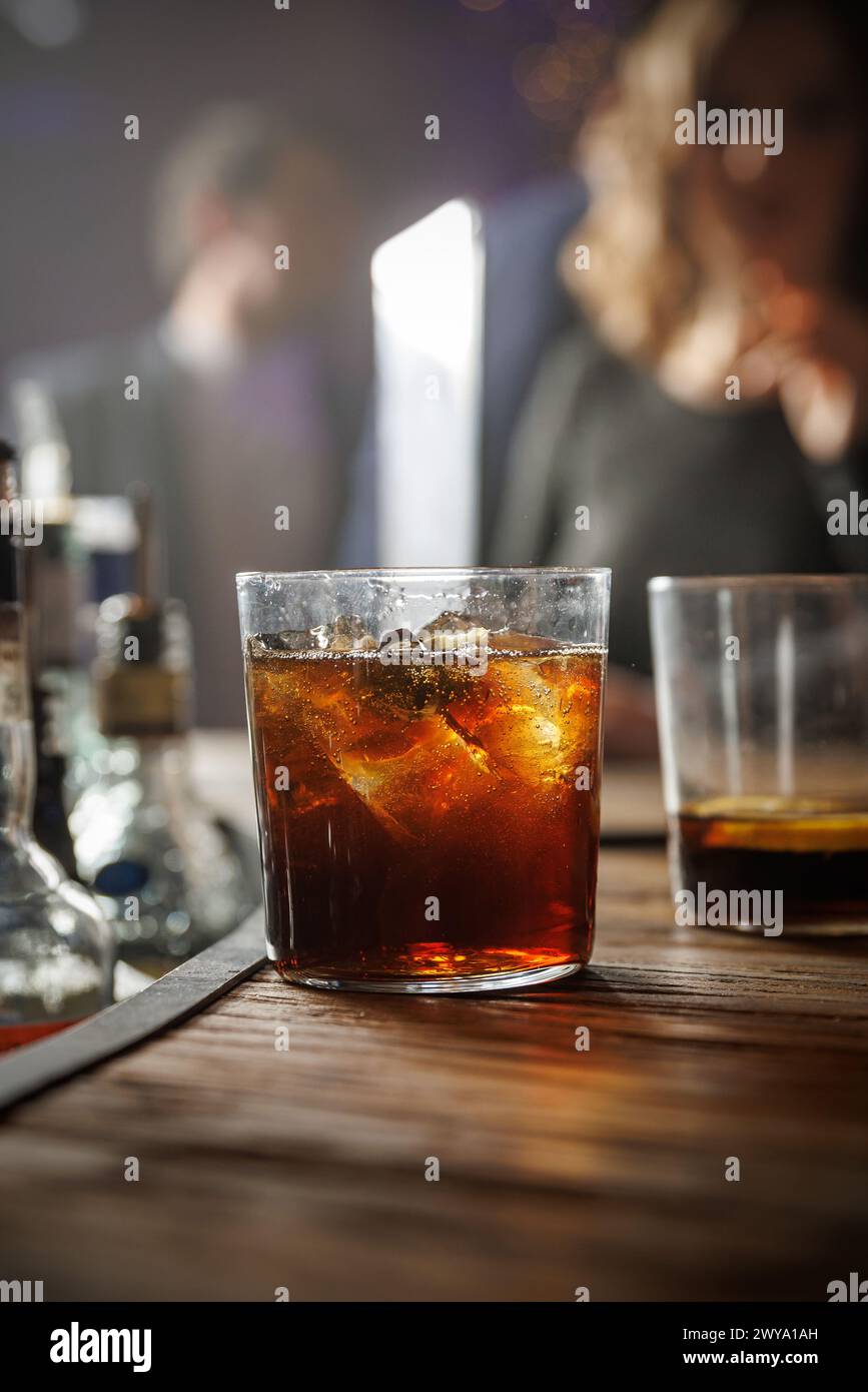 Gas bubbles of carbonated cola drink in a glass on a wooden bar counter ...
