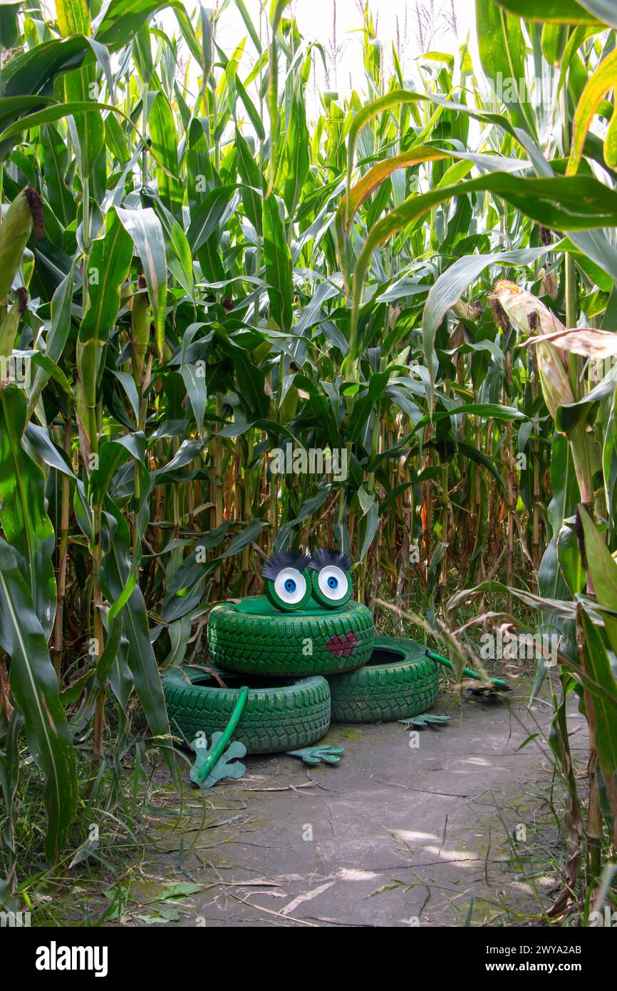 A vertical shot of recycled tire frog art installation in a cornfield ...