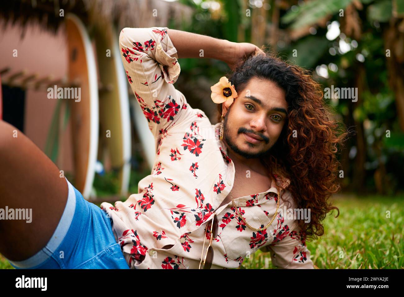 Gay man with floral shirt poses, holds flower, exudes confidence, style ...