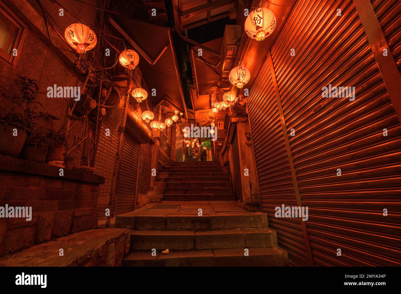 A narrow, quiet alley decorated with lanterns leading to a traditional ...