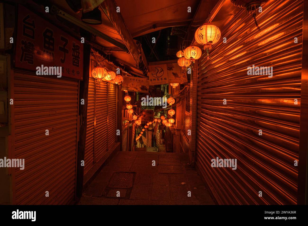 A narrow, quiet alley decorated with lanterns leading to a traditional ...