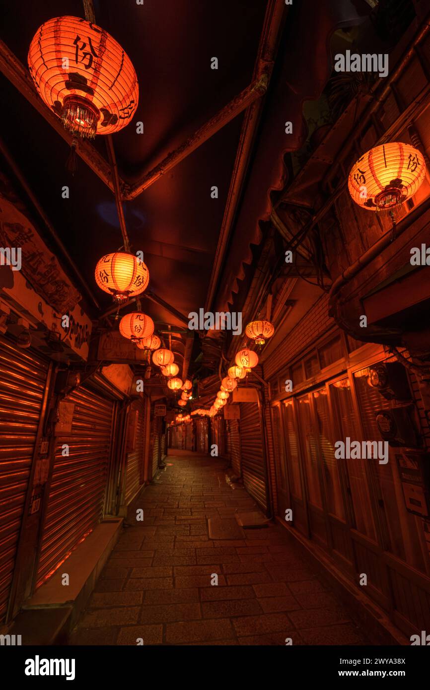 A narrow, quiet alley decorated with lanterns leading to a traditional ...
