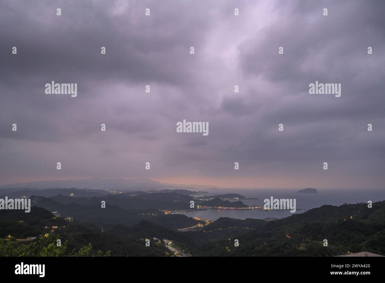 A picturesque evening scene showing a coastal town lit up beneath a ...