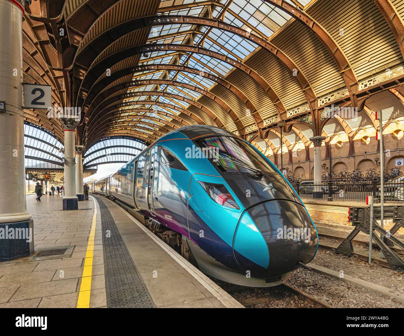 A train stands at a platform under a curving 19th Century historic ...