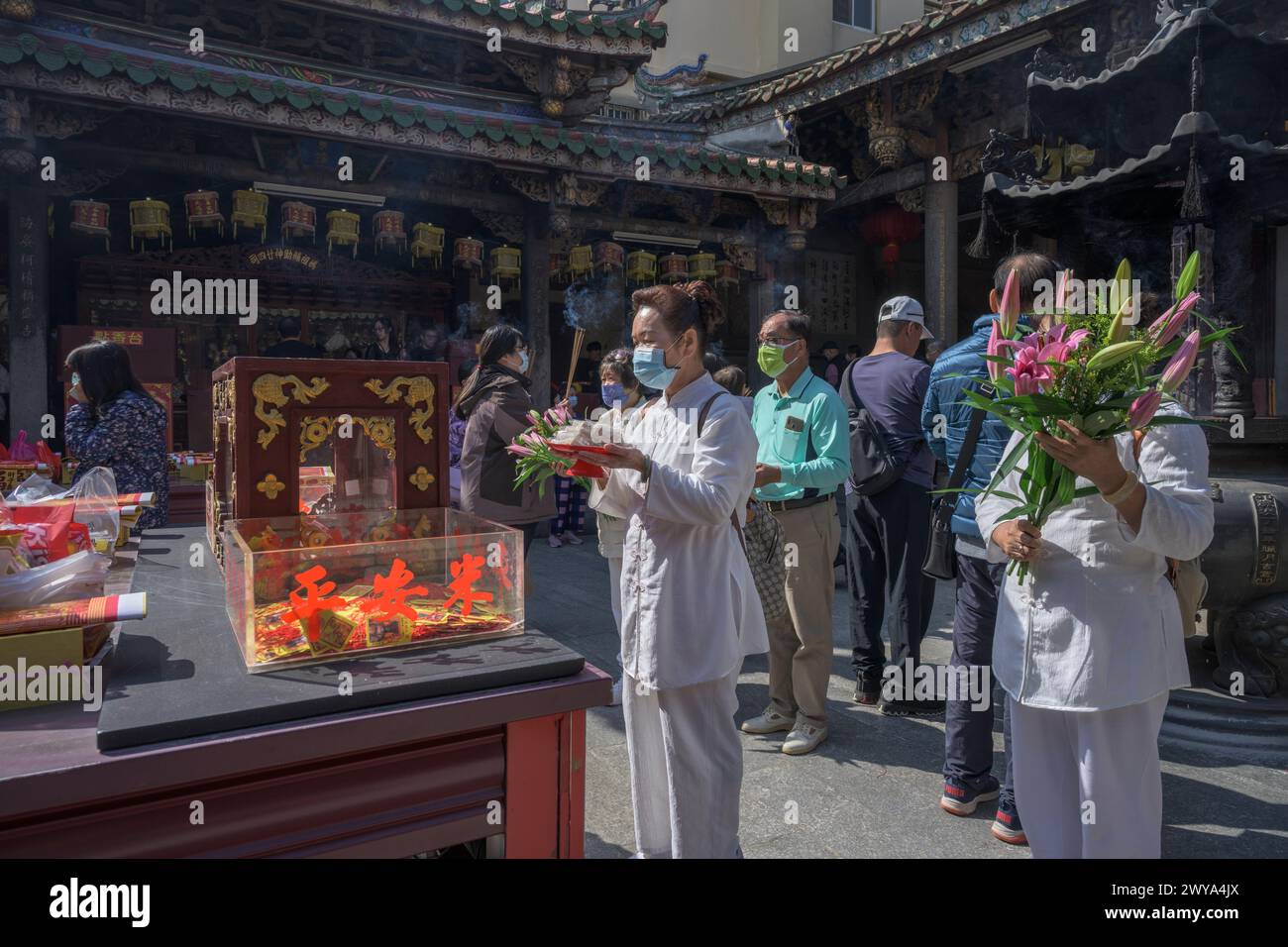 Devotees with floral offerings during a religious ceremony in a richly ...