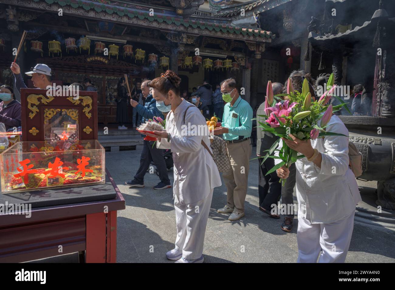 Devotees with floral offerings during a religious ceremony in a richly ...