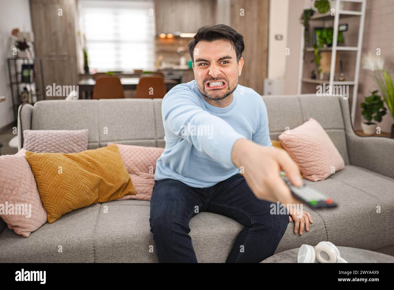Man Sitting on Couch Holding Remote Control Stock Photo - Alamy