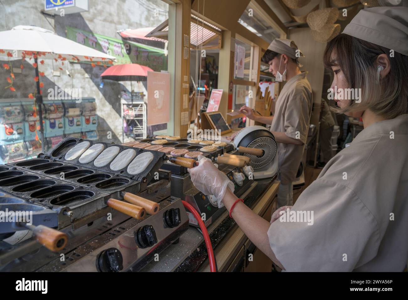 A local cook skilfully prepares traditional pancakes at a busy street ...