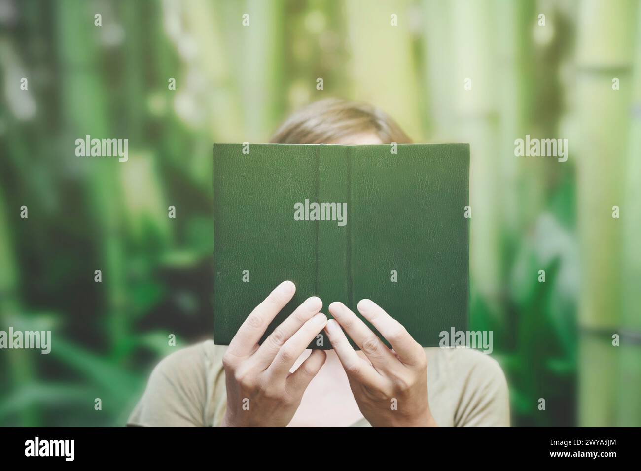 surreal moment of a person with a green book in front of his face ...