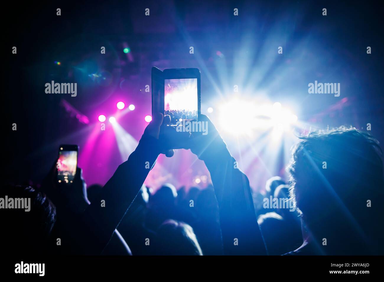 Filming a concert with a mobile phone, music and light show on stage ...