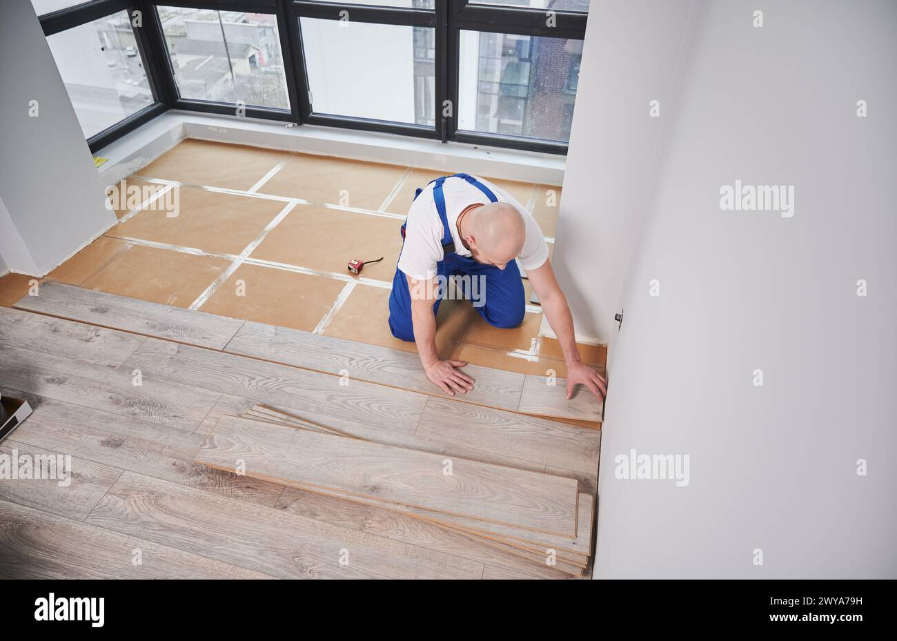 Top view of man construction worker laying laminate wood plank on floor ...
