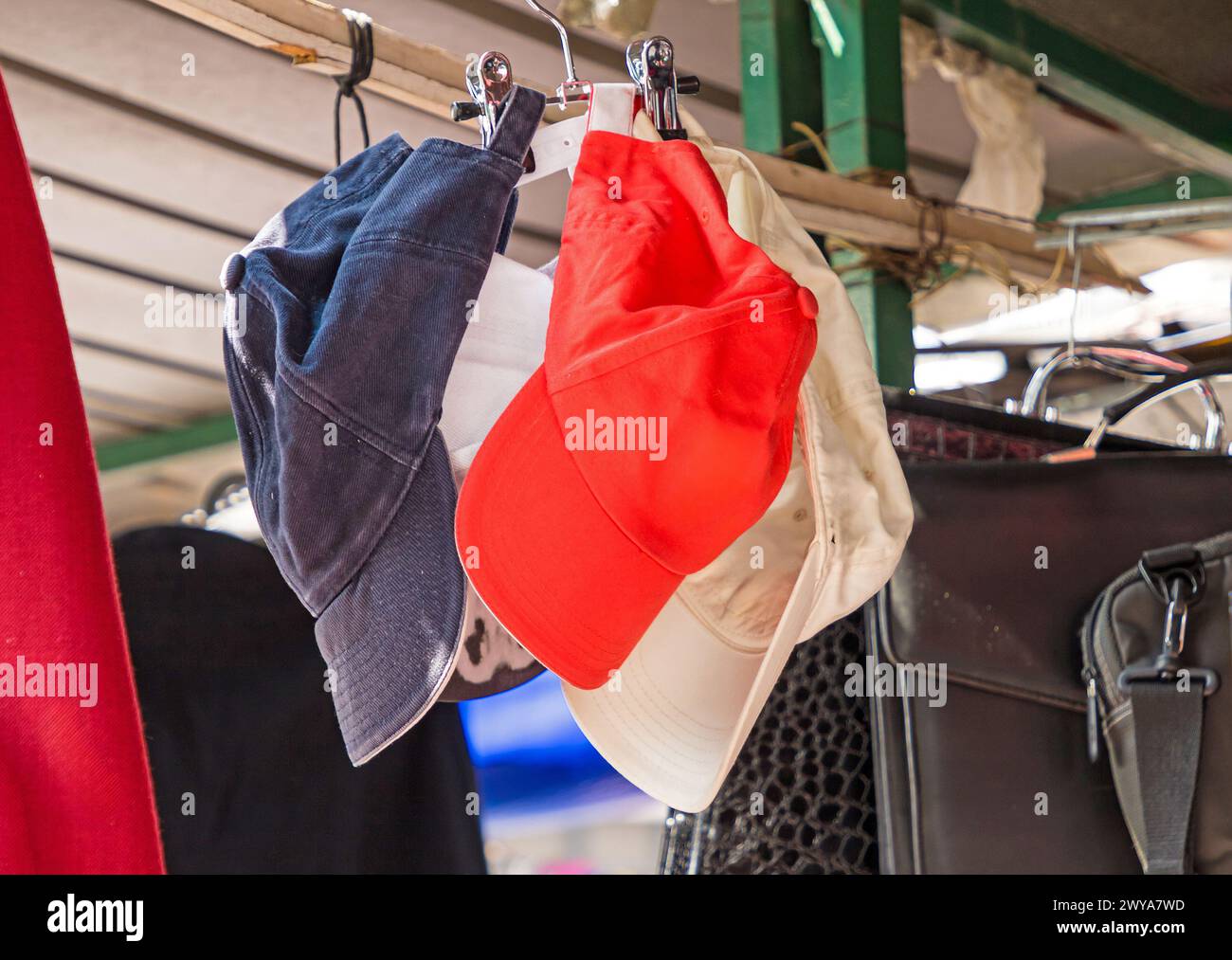 Colorful baseball caps hanging on a metal string outside in a market ...