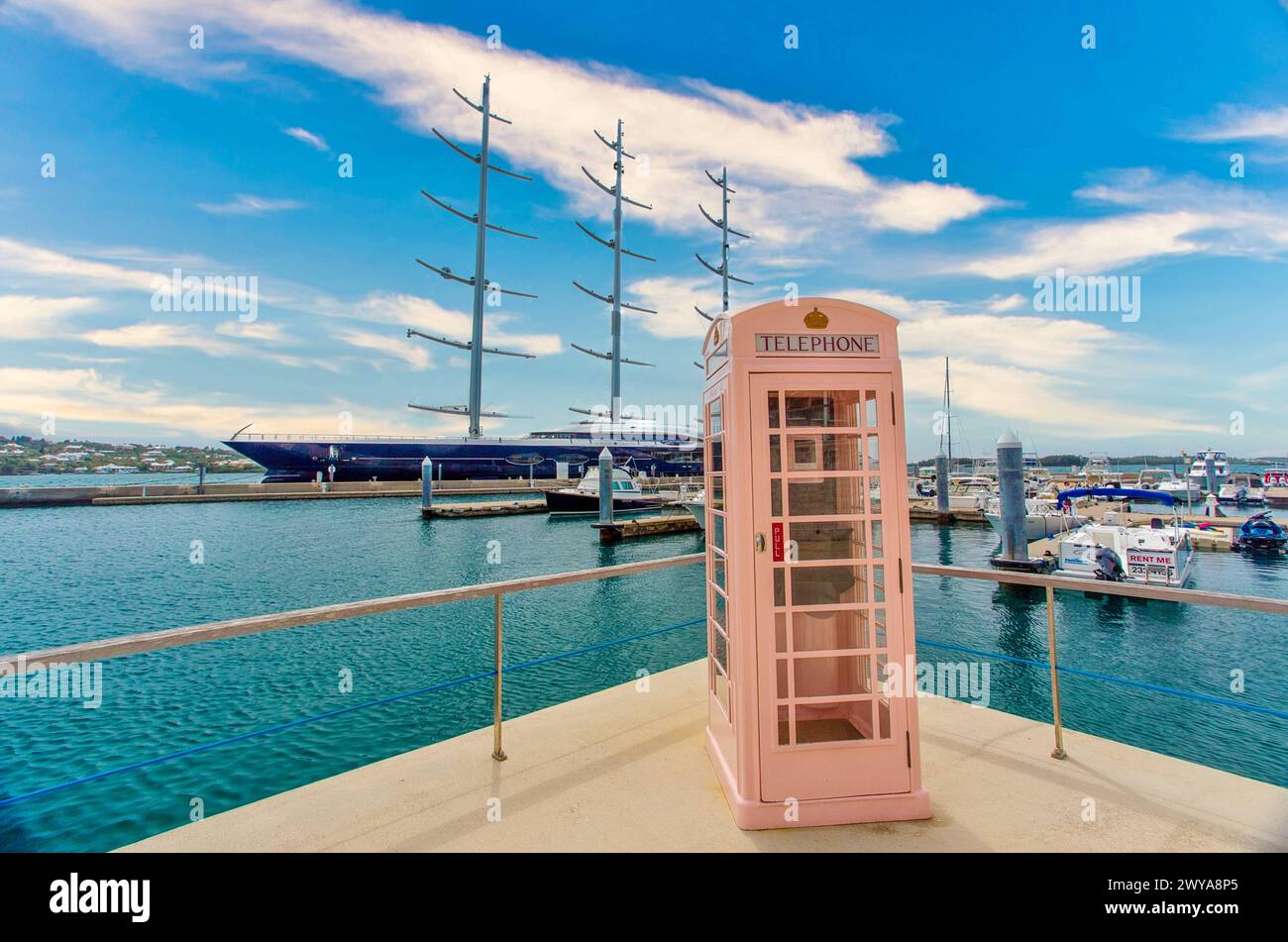 An old British telephone kiosk, with a three masted sailing ship moored ...