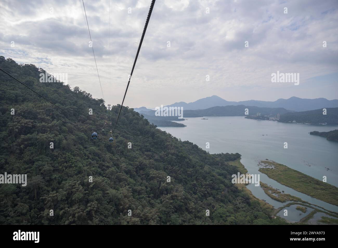 Cable cars hanging over Sun Moon lake surrounded by lush forests and ...