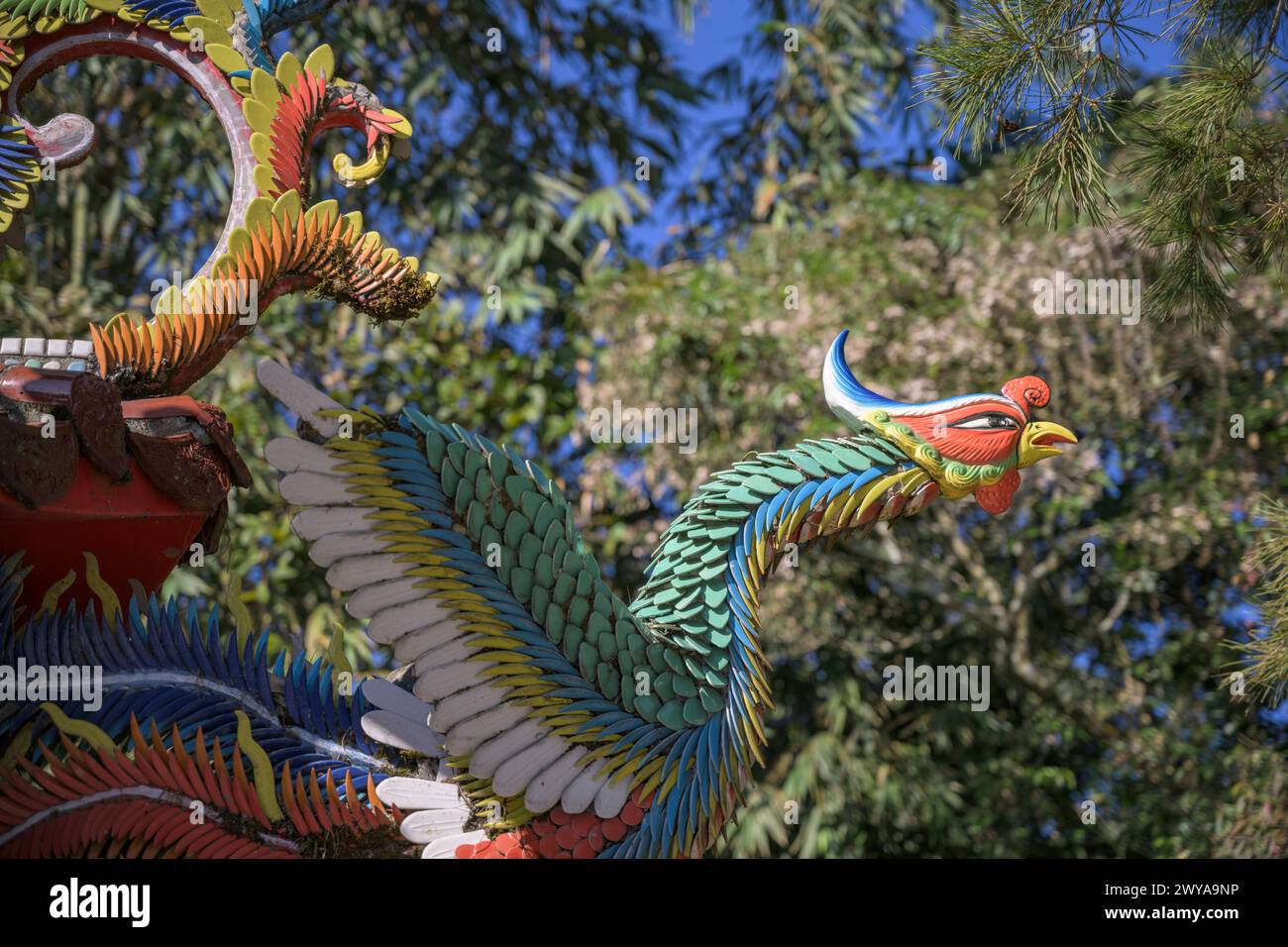 A vibrant dragon sculpture adorning a temple roof with a blue sky and ...