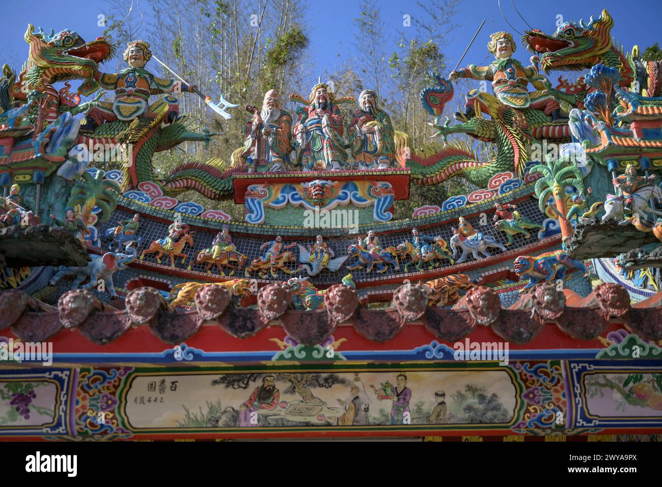 A vibrant dragon sculpture adorning a temple roof with a blue sky and ...