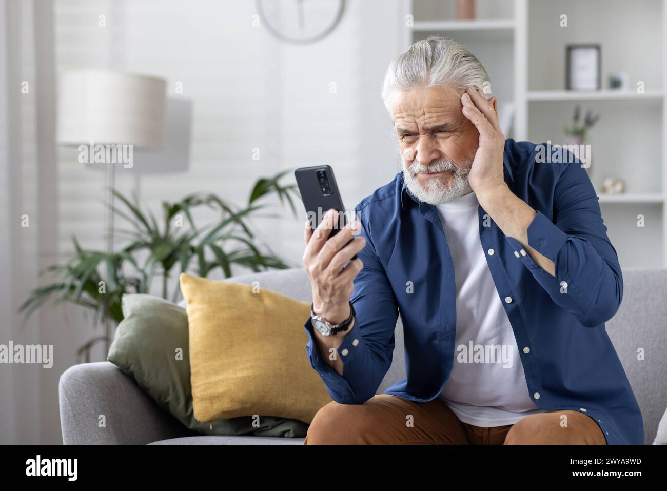 An elderly man with a beard appears puzzled or concerned while trying ...