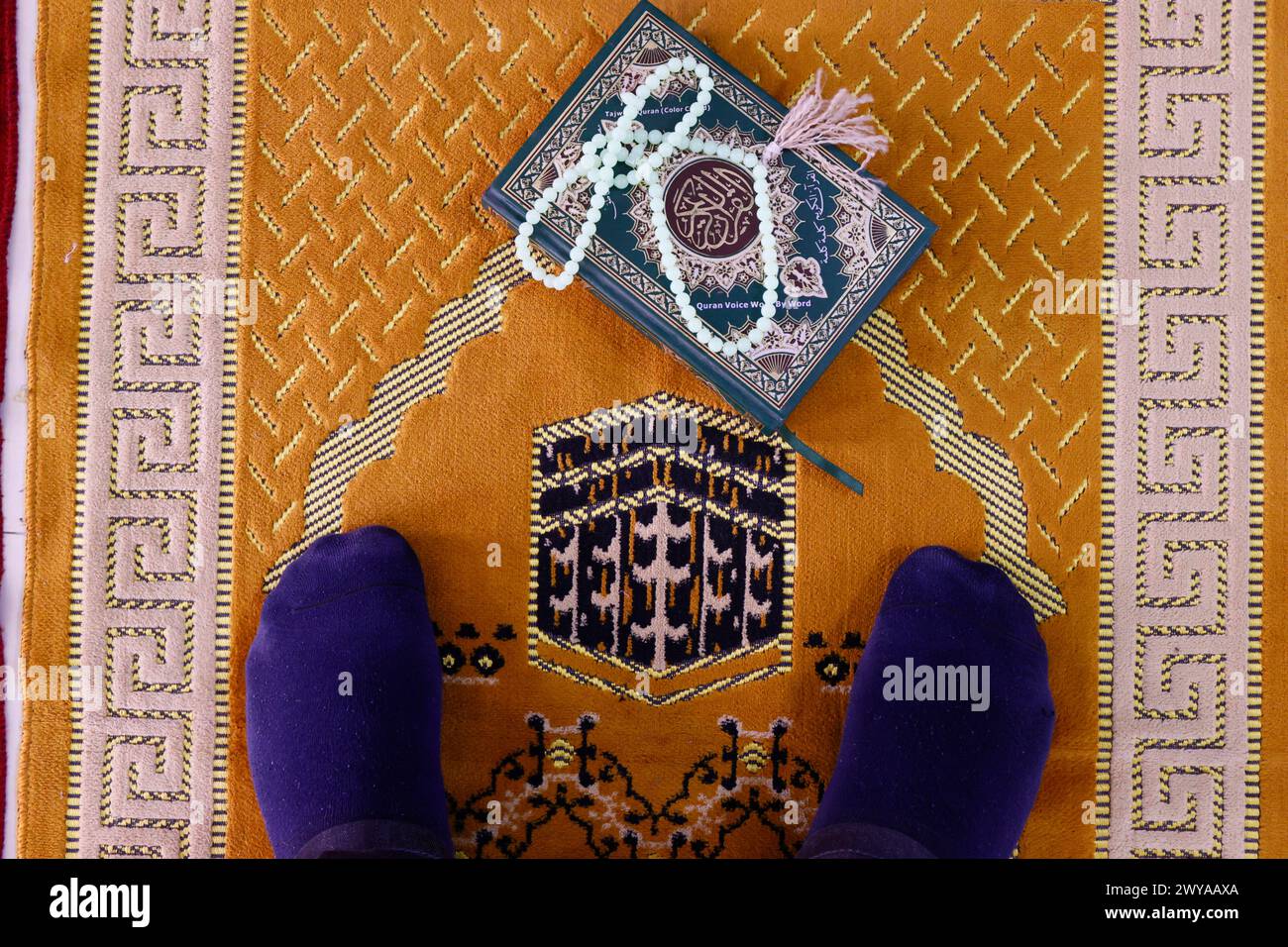 Muslim man praying on Islamic prayer mat with the Kaaba, Symbol of ...