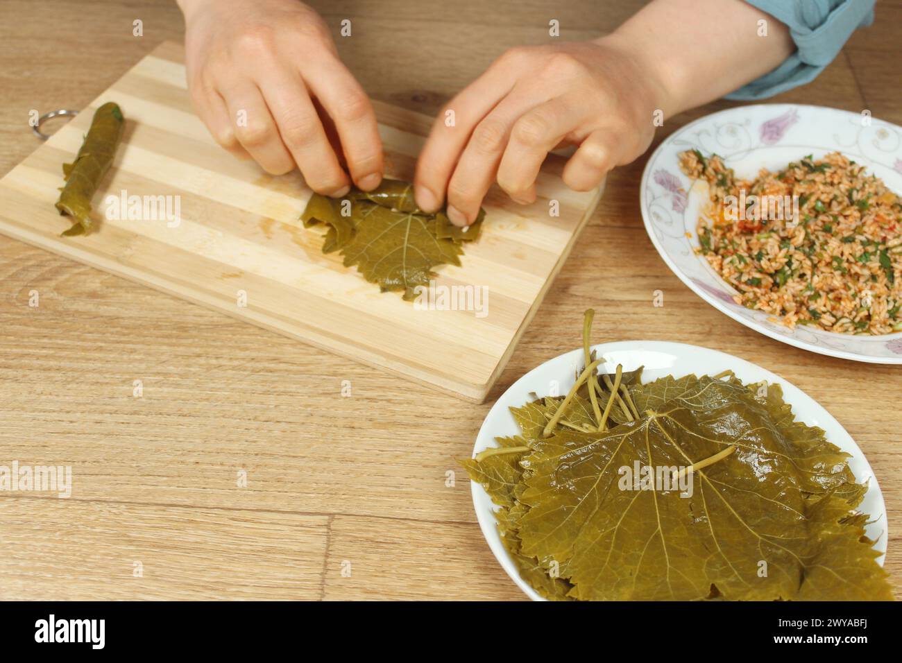 Woman hands preparing wrap stuffed with rice ingredient. Greek or ...