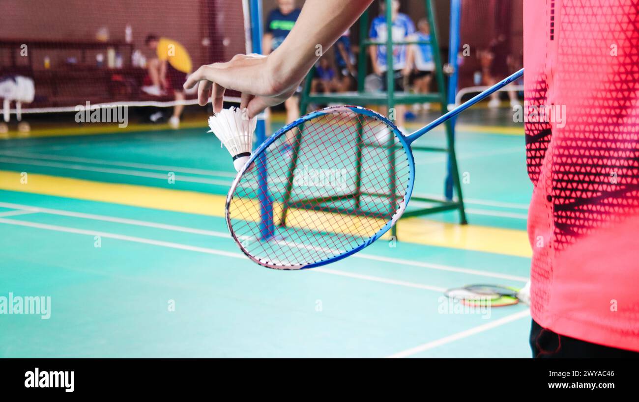 The badminton player holding a white shuttlecock and racket and ...