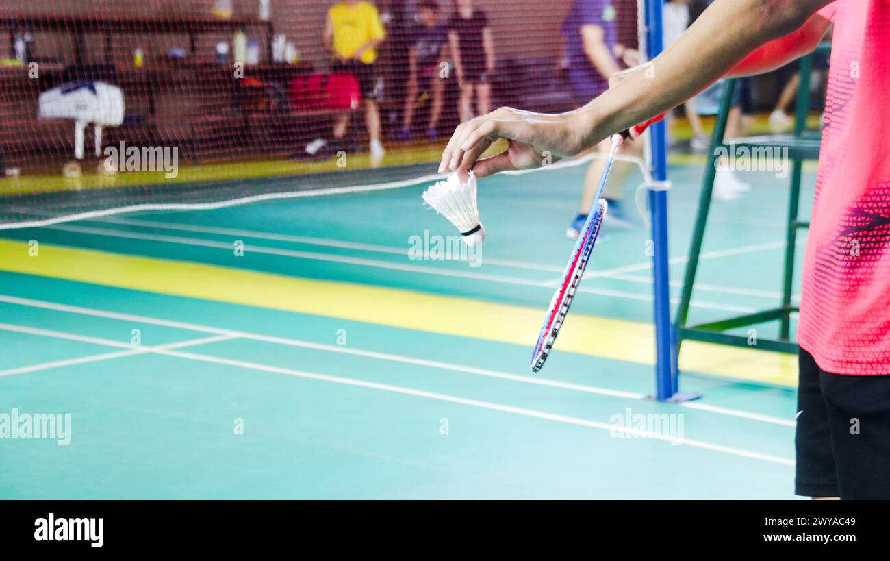 The badminton player holding a white shuttlecock and racket and ...