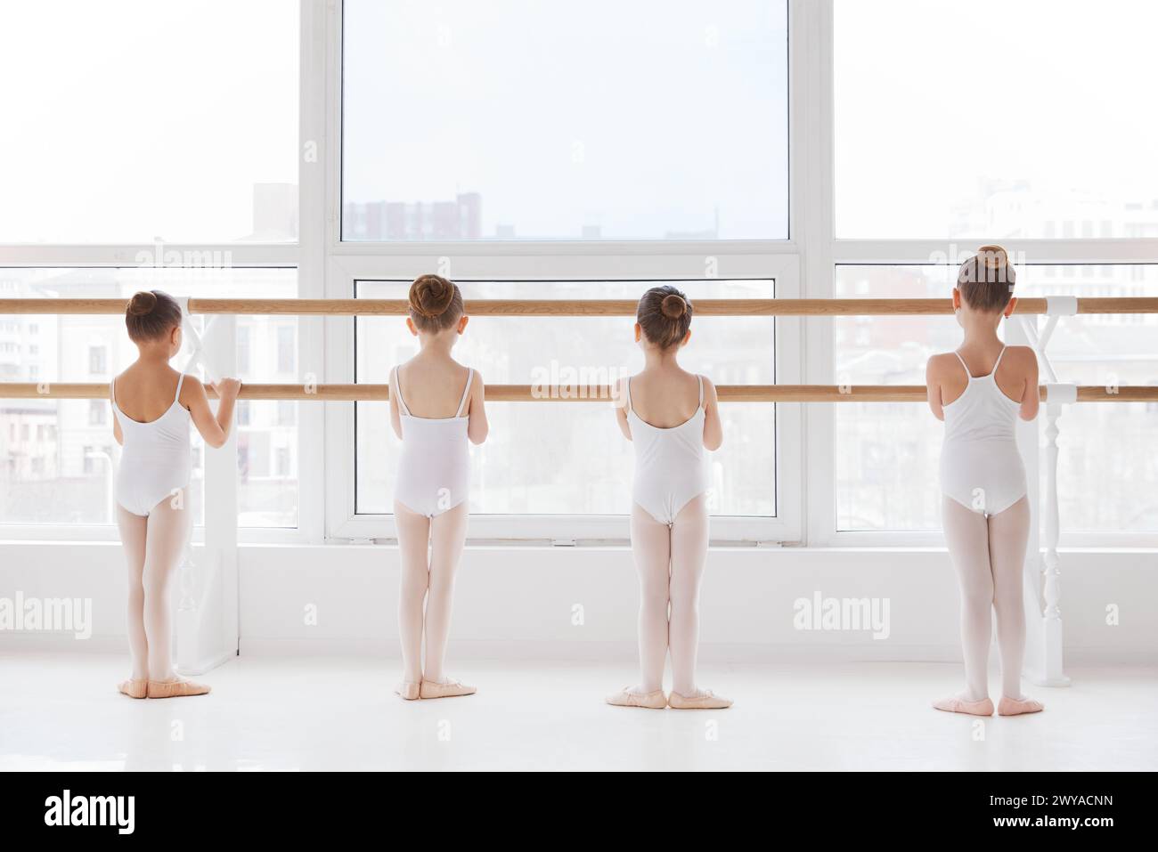Rear view photo of little girls in ballet attire practicing poses in ...