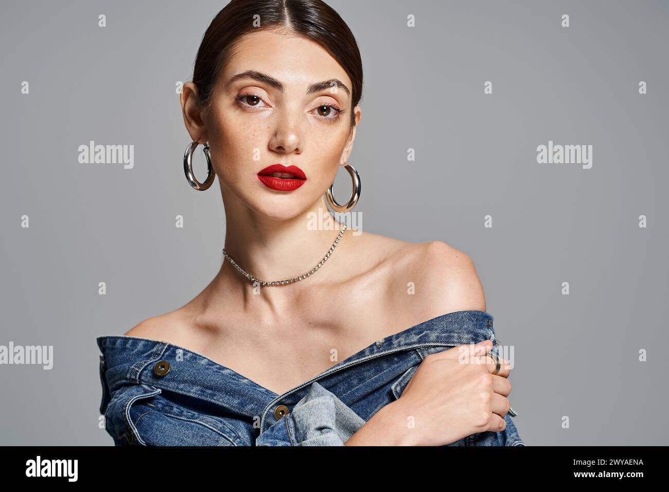 Brunette woman slaying in a denim dress, with striking red lips ...