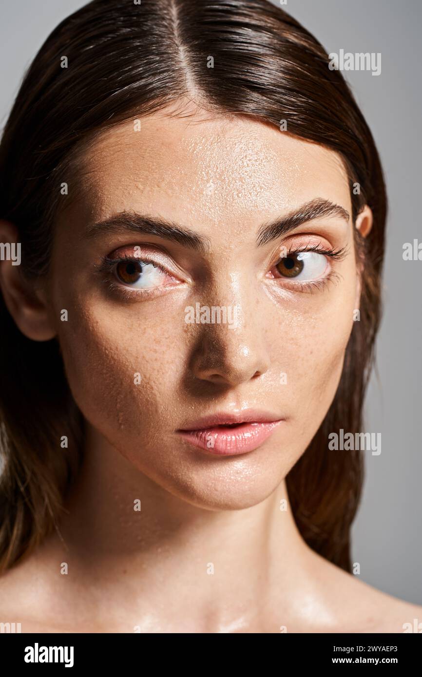 A young woman with water drops on her face, exuding connection with ...