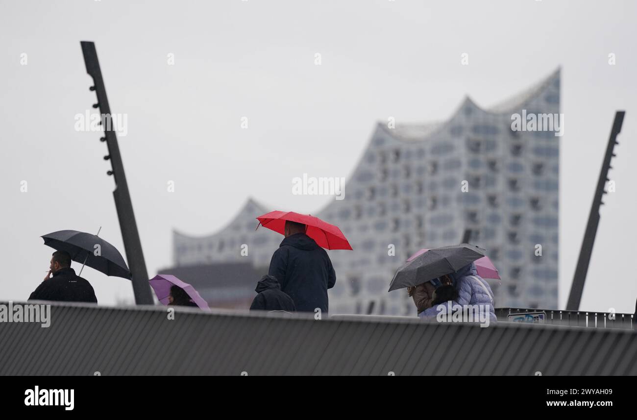 05 April 2024, Hamburg: Passers-by walk in the pouring rain on the Jan ...