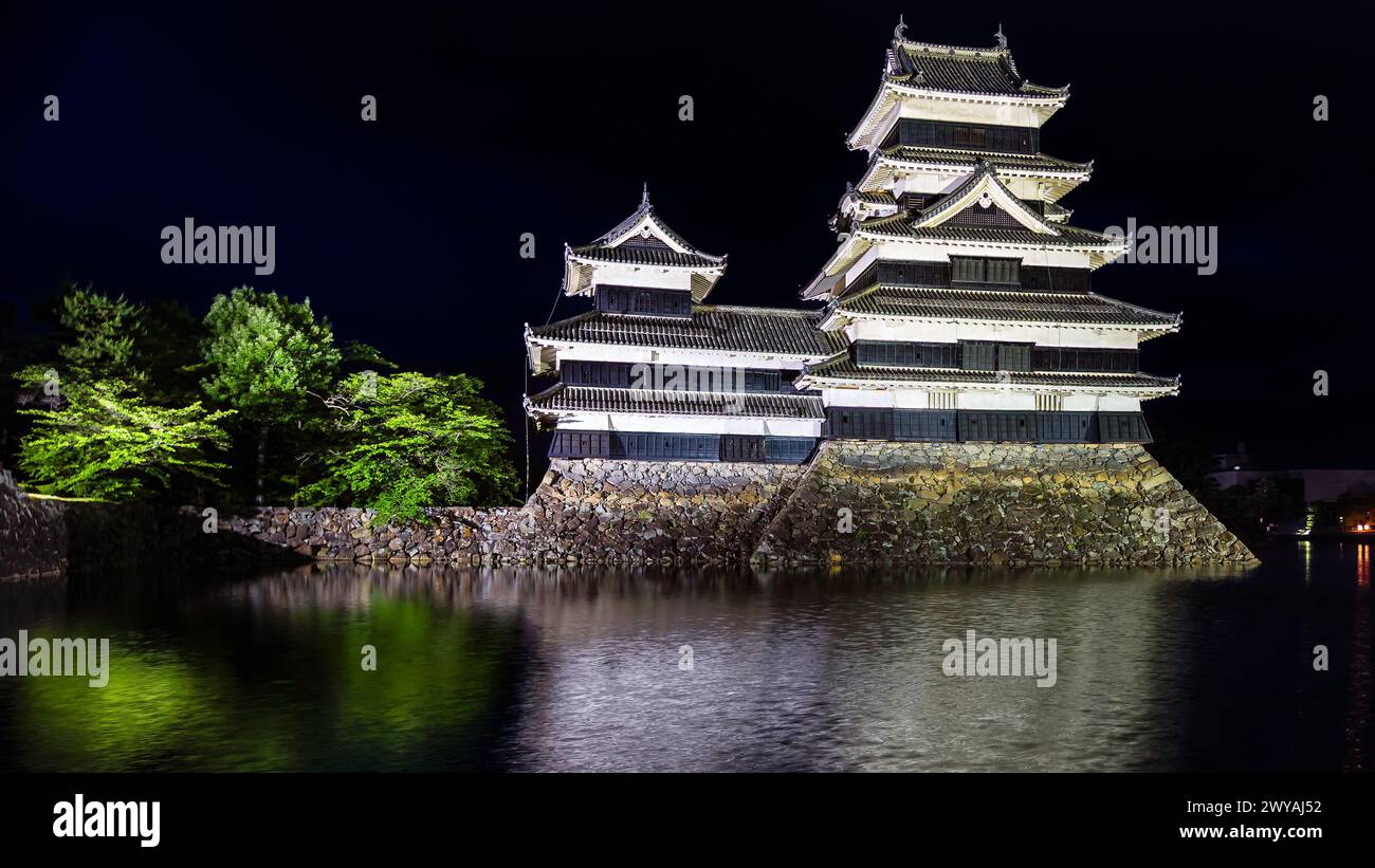 Old Japanese castle at night with reflection in its moat (Matsumoto ...
