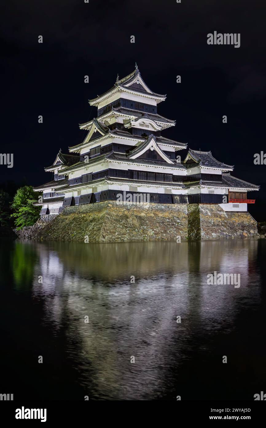 Old Japanese castle at night with reflection in its moat (Matsumoto ...