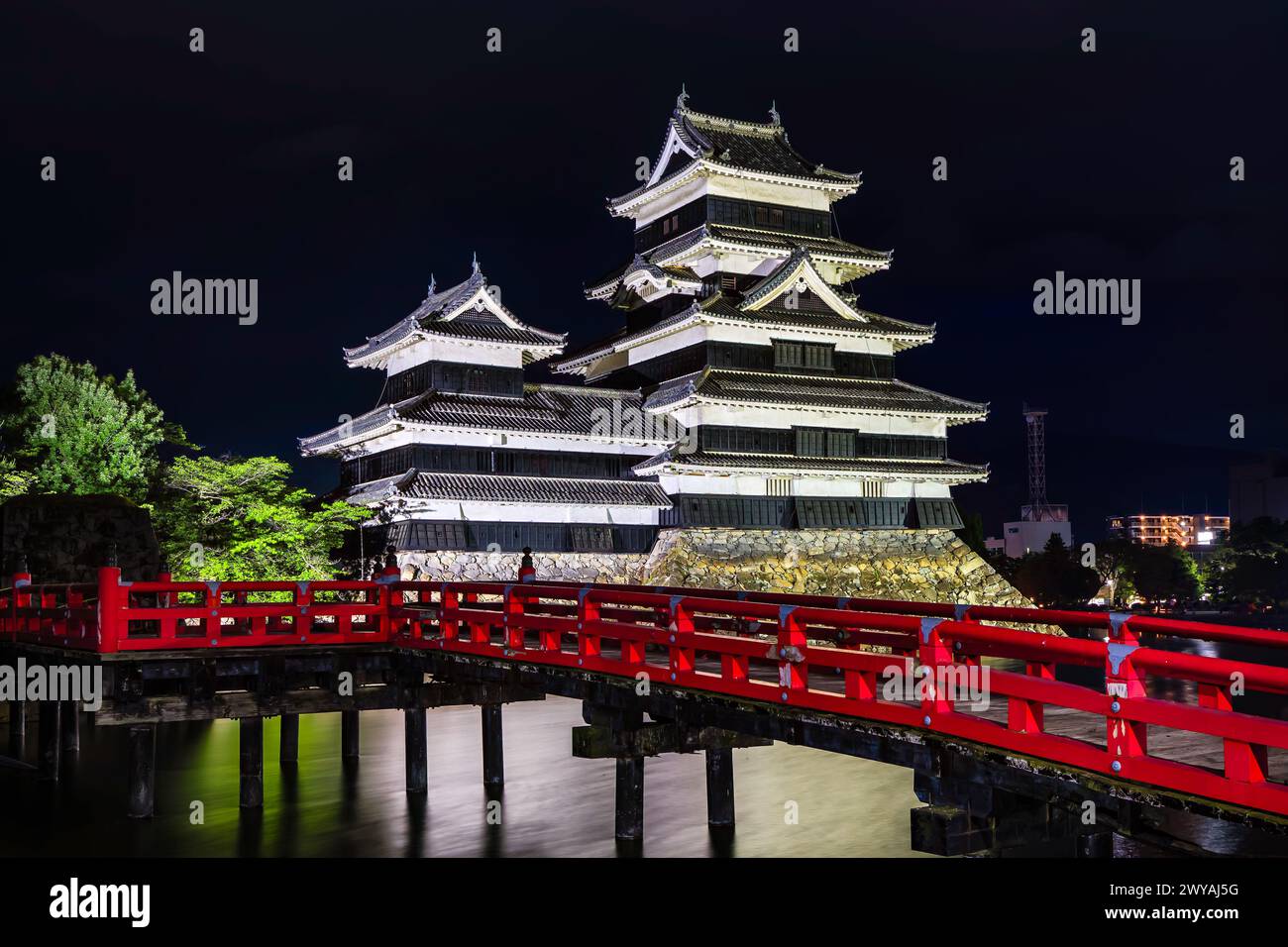 Japanese Castle and red bridge at night with a reflection in its moat ...