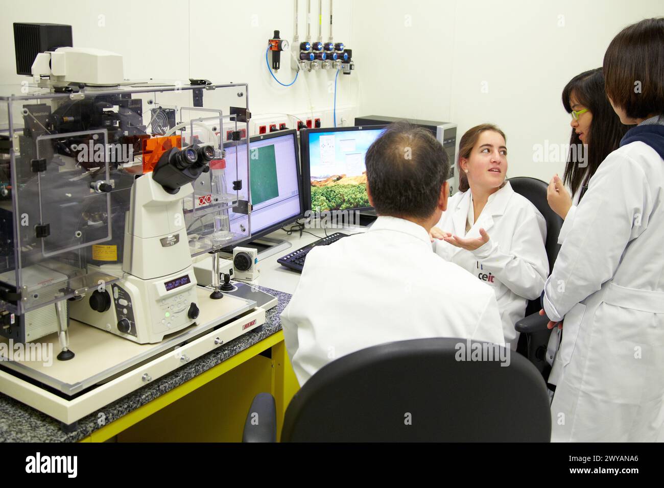 Teacher and students. Inverted optical microscope. With incubator ...
