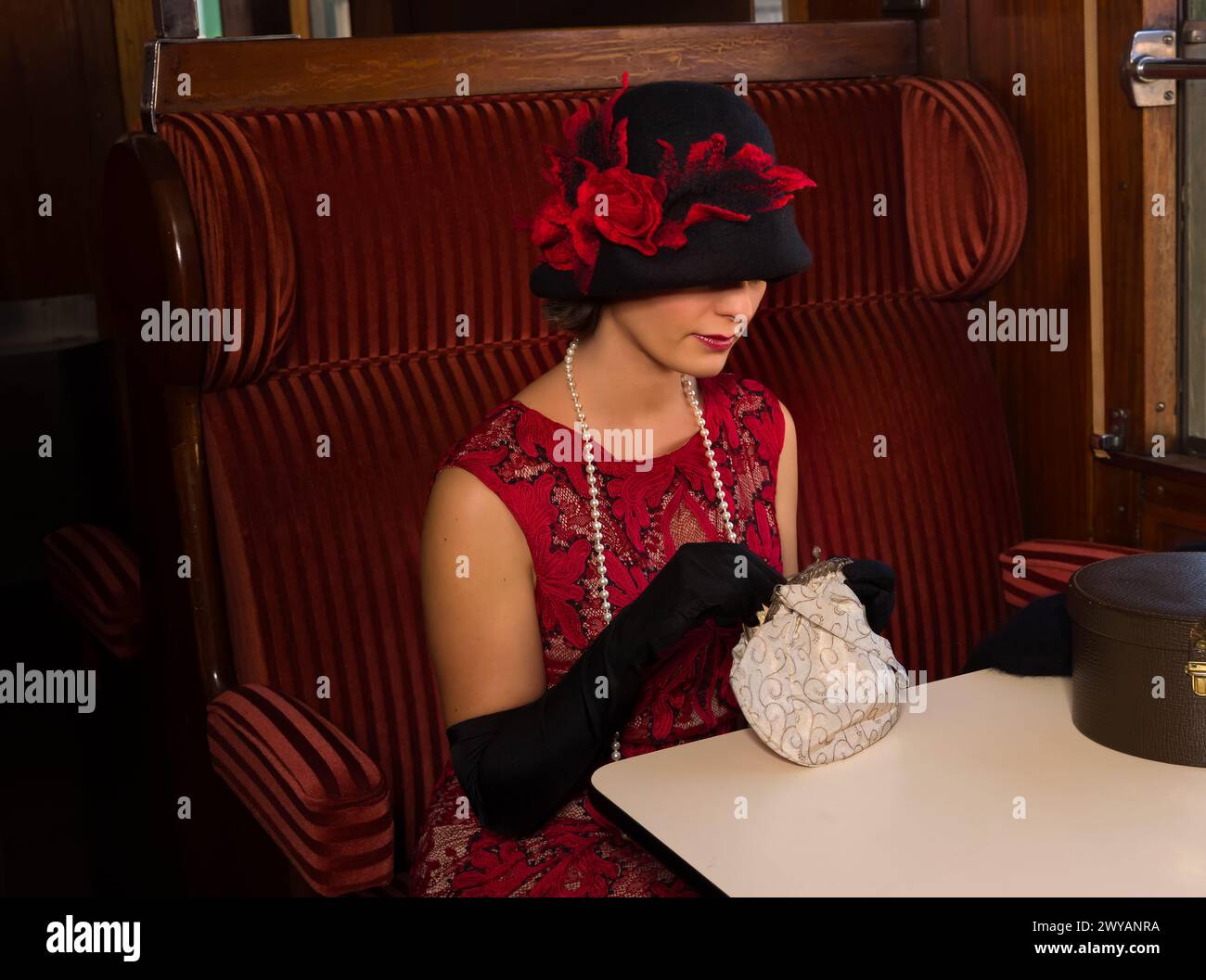 Attractive 1920s woman in red flapper dress and cloche hat posing in ...
