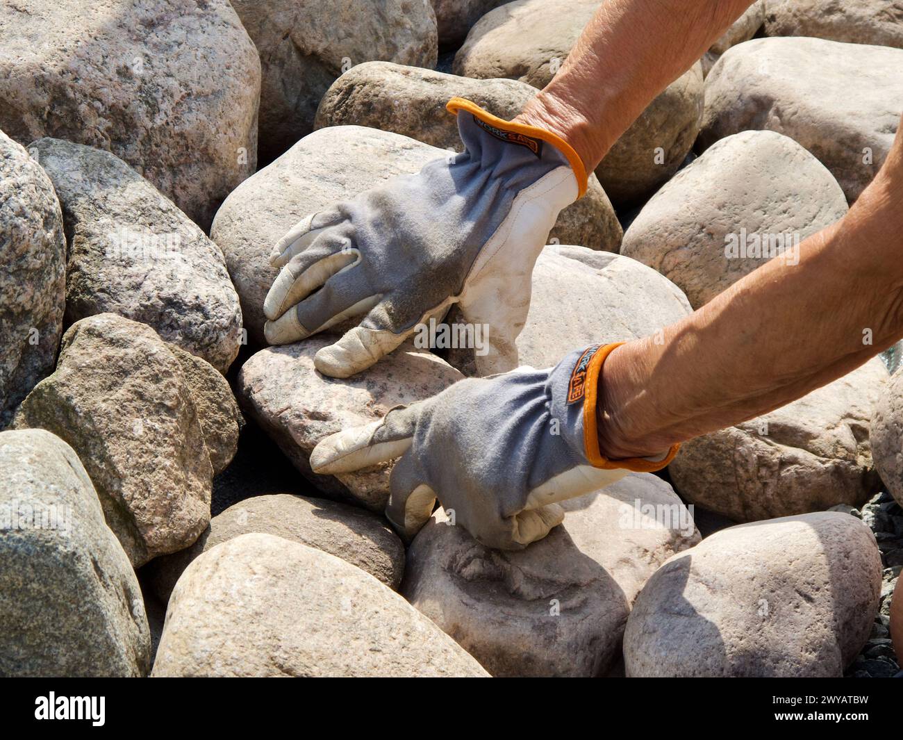 Women hands with work gloves adds a heavy grey stone in a stone setting ...