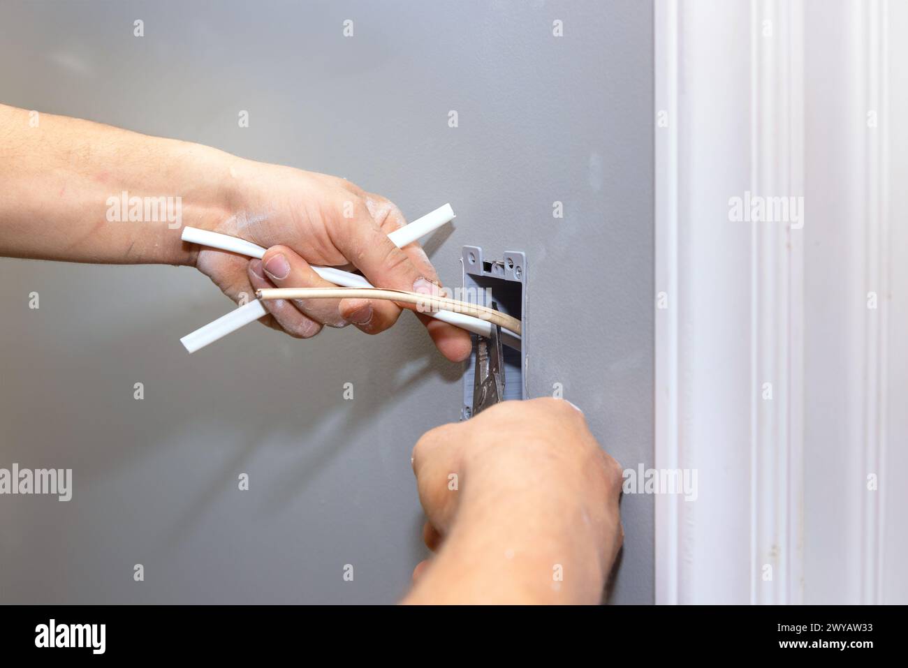 During renovations, electrician connects an electrical outlet to wall ...