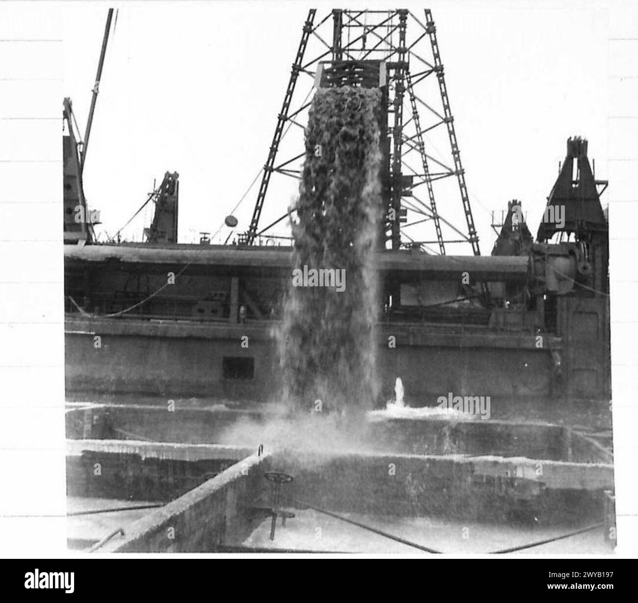 Dredger pumps sand into breakwater units at a prefabricated port under ...