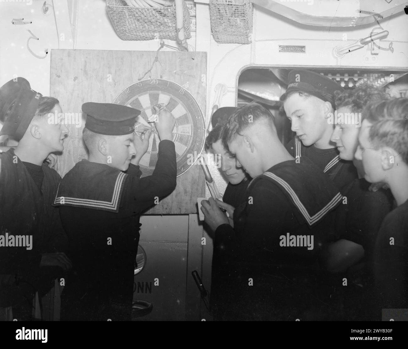 In October, boys aboard a battleship at Rosyth Naval Base are shown ...