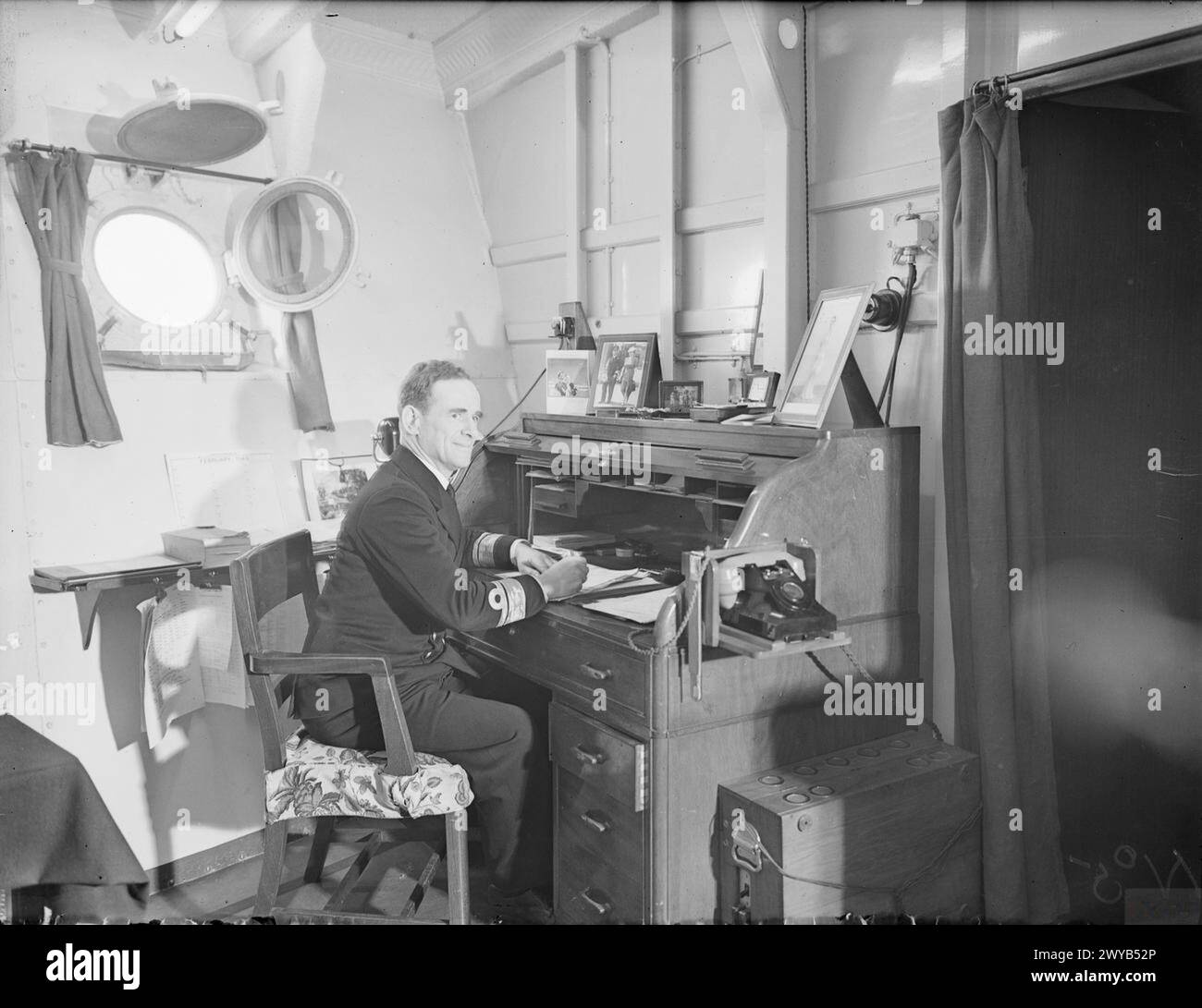 COMMODORE 1ST CLASS M M DENNY, CB, AT HIS DESK ABOARD HMS KING GEORGE V ...
