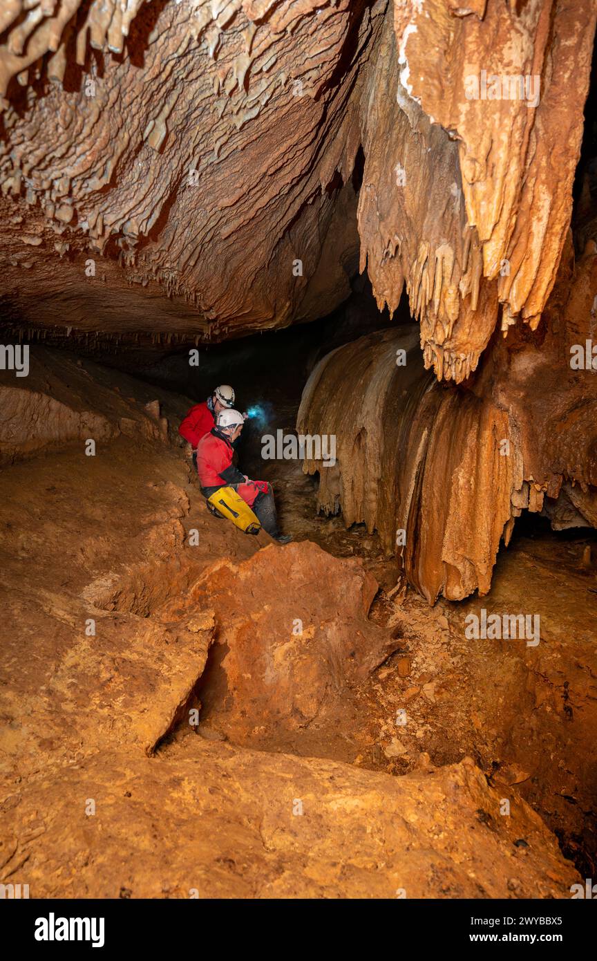 A group of speleologist inside a cave, illuminated by headlamps ...