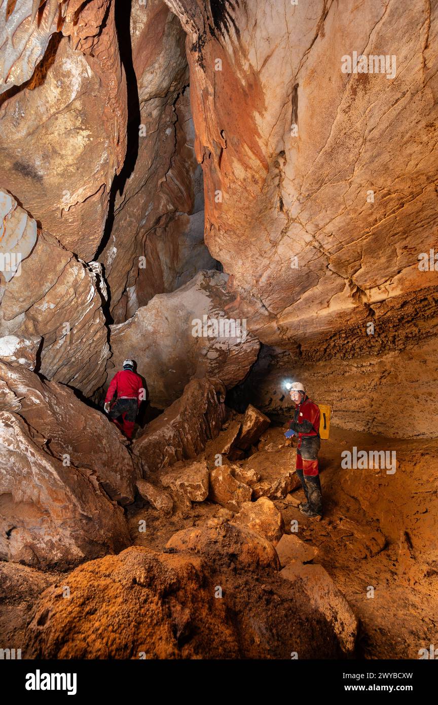A group of speleologist inside a cave, illuminated by headlamps ...