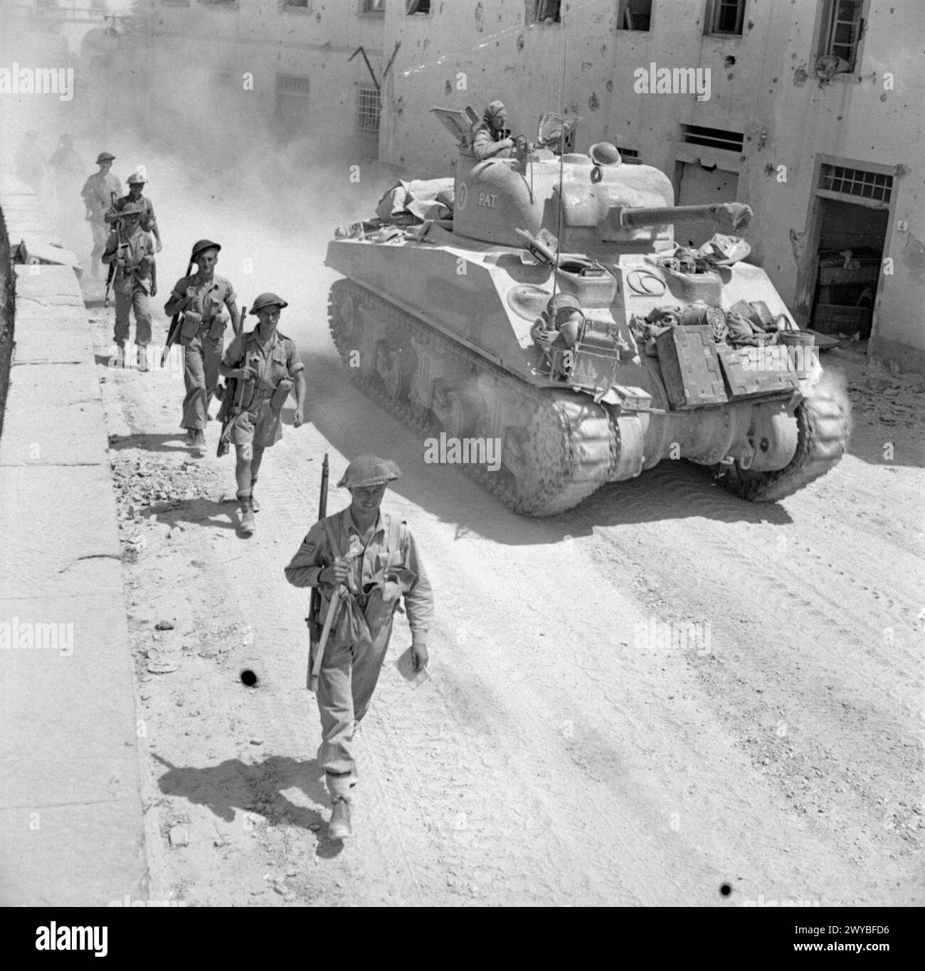 A Sherman tank accompanied by British infantry advances through ...