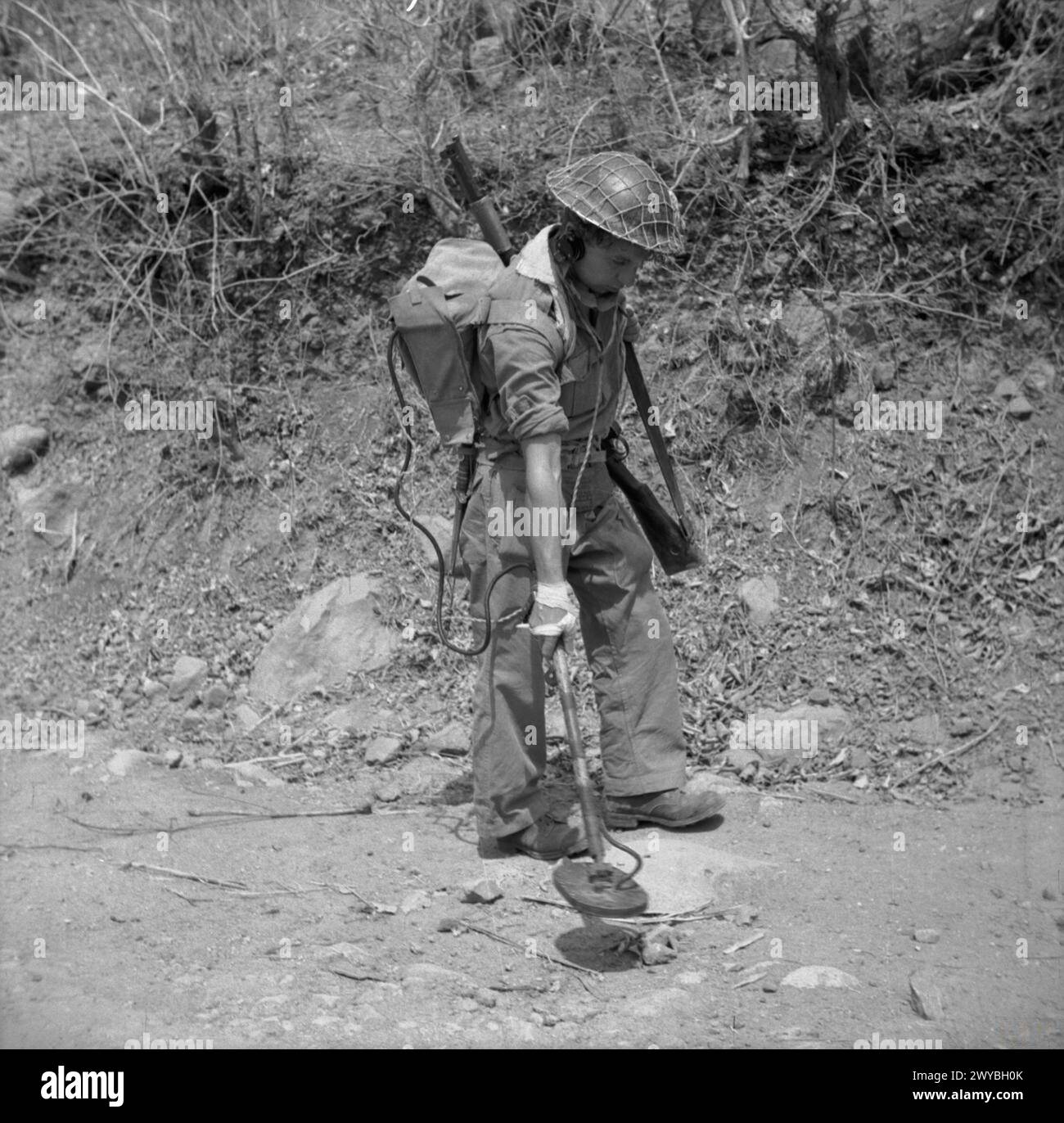 A Royal Engineers sapper of the British Army uses a detector to search ...