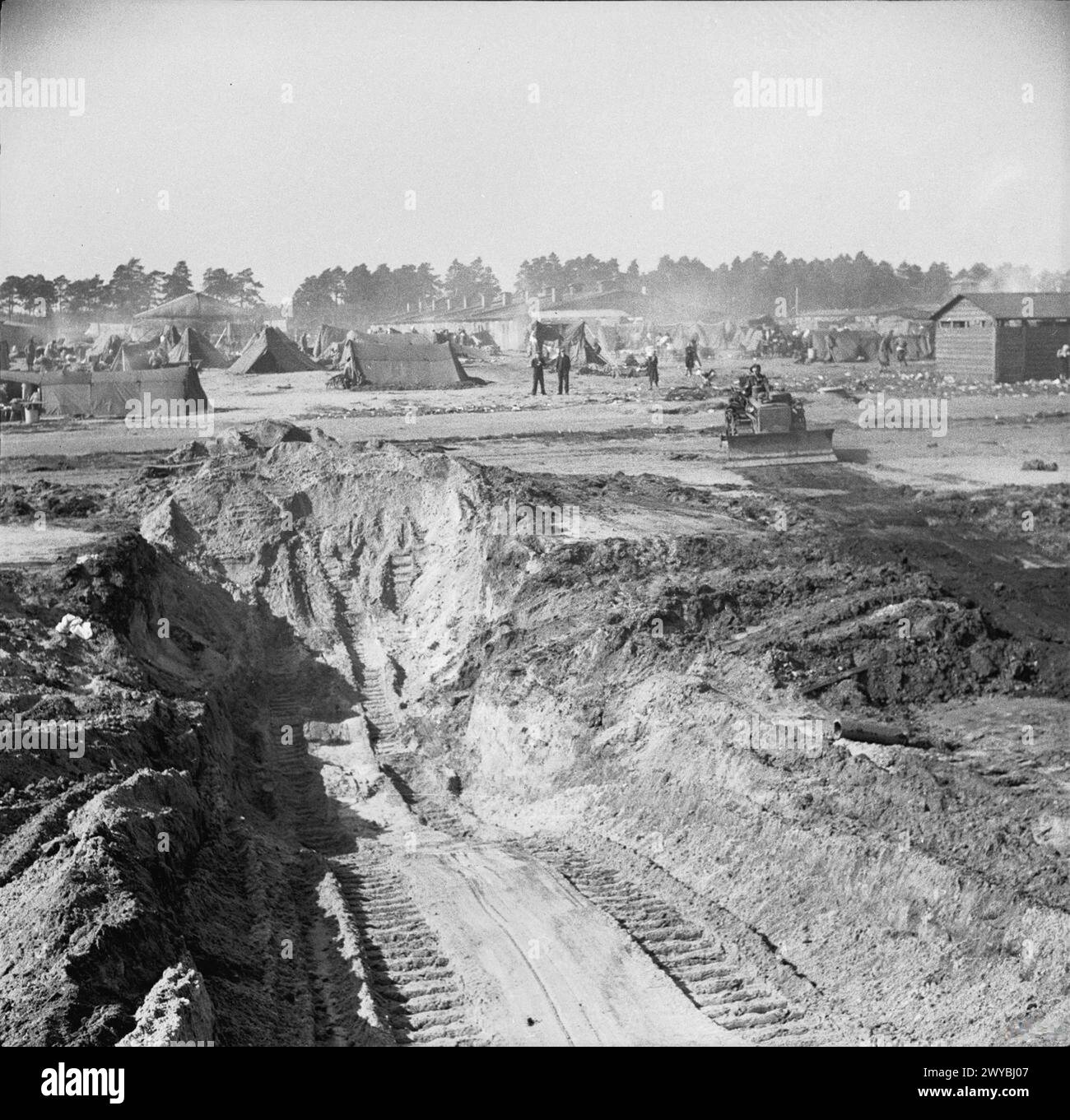 A partially excavated mass grave at Bergen-Belsen shows tents for ...