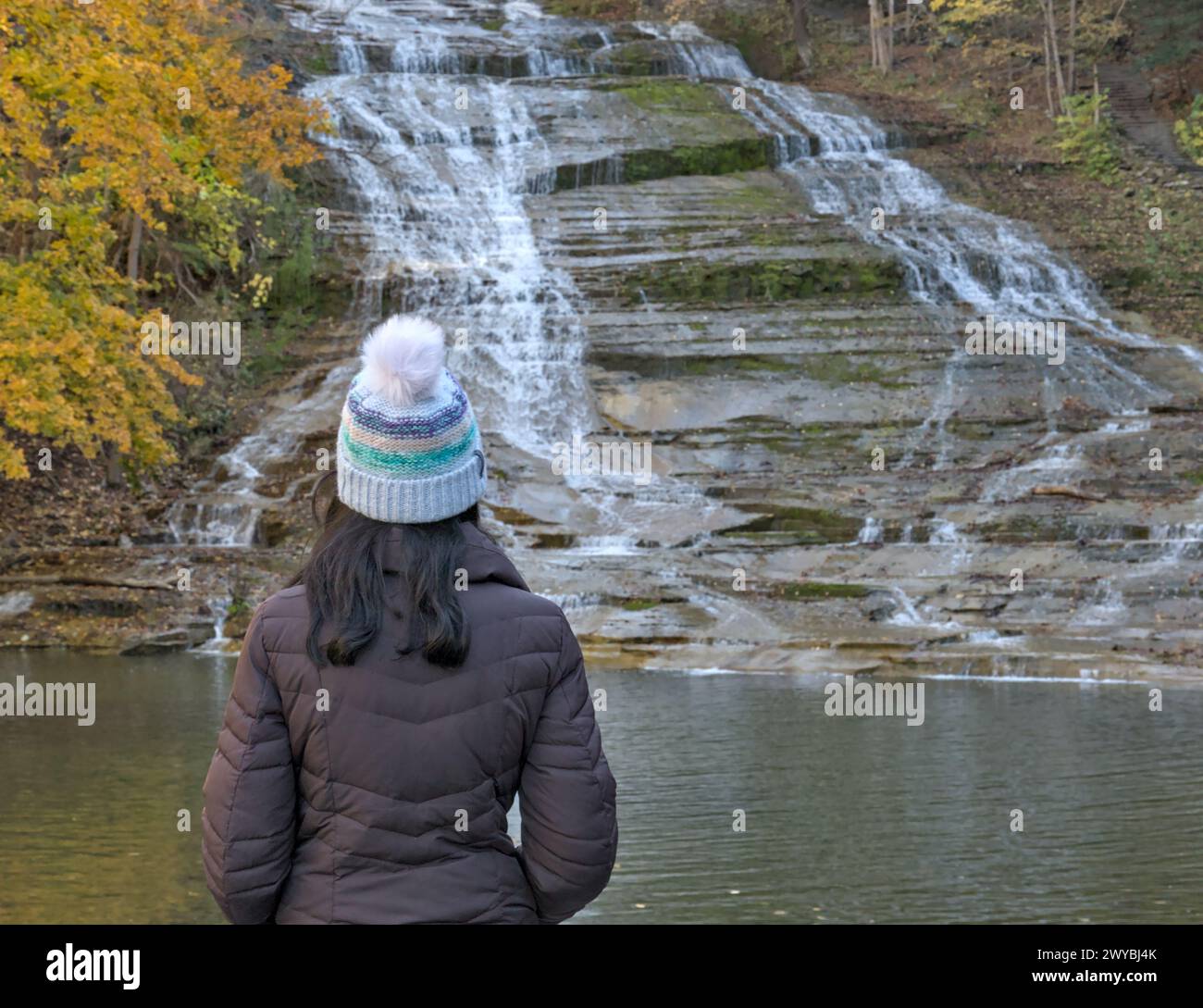 woman looking at a waterfall on a nature hike (photographed from behind ...