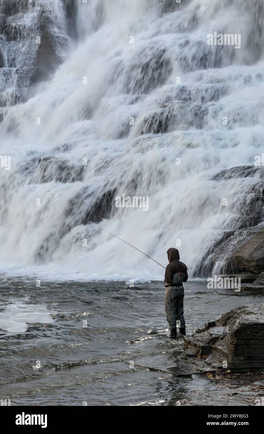 man with fishing rod in creek (shot from behind, no face ...